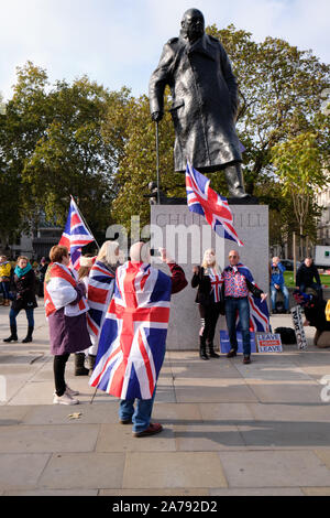 Protesters draped in Union Jack flags walk past a banner on the way to ...