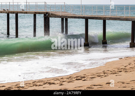 Waves under jetty at the beach Stock Photo - Alamy