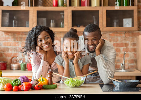 Adorable black family cooking healthy dinner together at kitchen ...