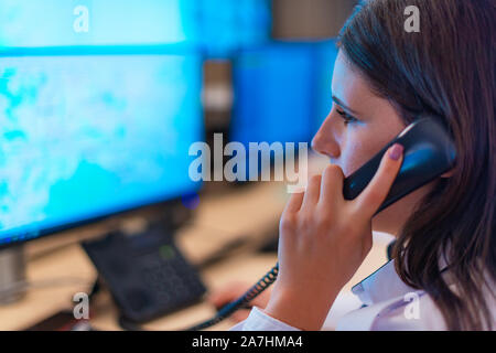 Female security guard operator talking on the phone, calling in the ...