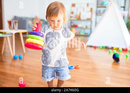 Adorable toddler building pyramid using hoops around lots of toys at ...