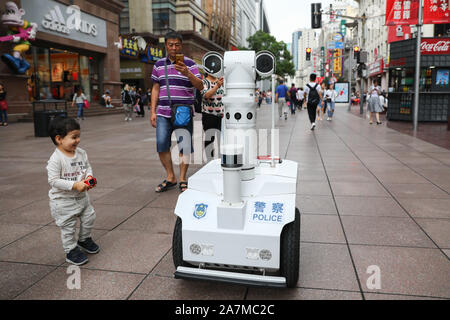A child plays with the robot patrolman on Nanjing East Road in Shanghai ...