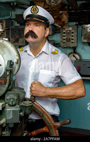 A sailor officer - old salt in the uniform is steering the ship with a ...