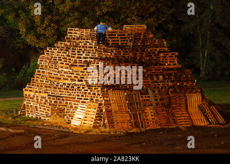 A Guy Fawkes bonfire mascot sits on top of a bonfire waiting to be lit ...
