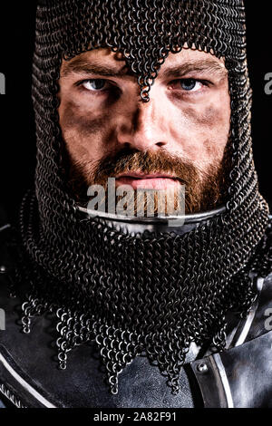 handsome knight in armor looking away and holding sword on black ...