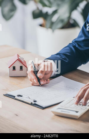 Cropped hands using calculator and writing in notebook for tax ...