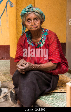 A native Guatemalan woman in traditional dress braids the hair of a ...
