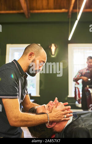 Barber shaving caucasian man in barber shop Stock Photo - Alamy