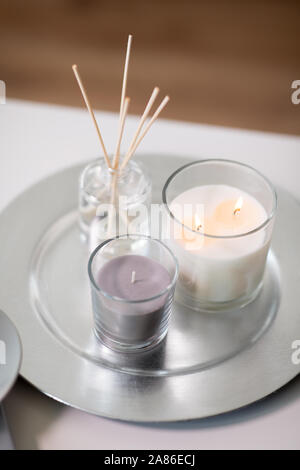 Burning candles and reed diffuser on table near color wall Stock Photo ...