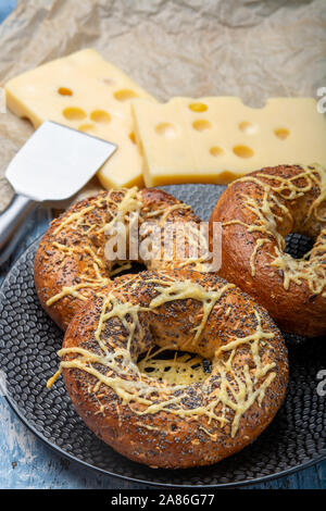 Tasty baked bagels with melted cheese and piece of aged Dutch Gouda ...