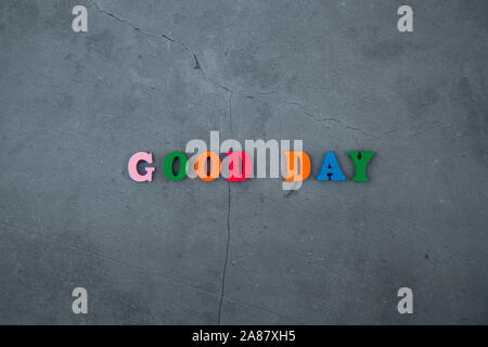 The multicolored good day word is made of wooden letters on a grey ...