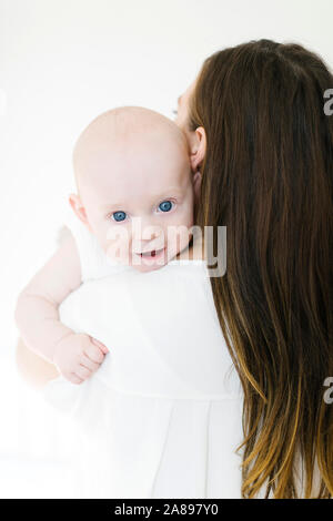 Child looking over her mothers shoulder Stock Photo - Alamy