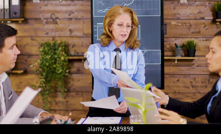 Confident female director giving charts to new investors. Breaking ...