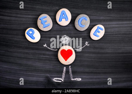 Pebble with peace symbol inside chalk drawing of man and letters PEACE ...