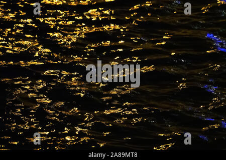 Water surface. The oily sheen of the night waves in the lamplight. Oil ...