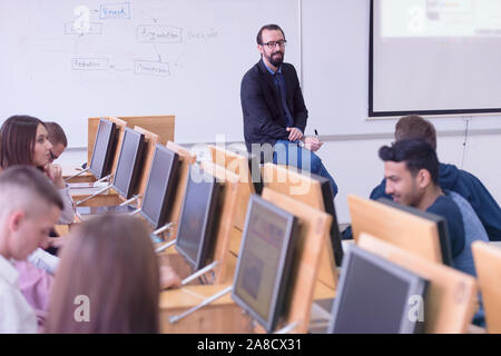 Group of students study with professor in modern school computer lab ...