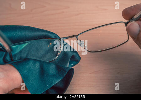 Cleaning glasses. A man wipes his glasses with a cloth. Storage and ...