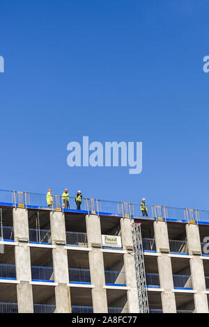 Workmen stand on the roof of a huge high rise Hilton Hotel development ...