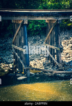 Railroad track across a rickety wooden trestle with stagnant water ...