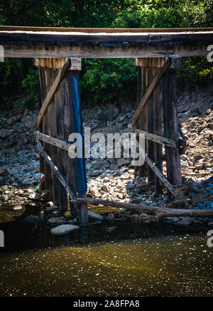 Railroad track across a rickety wooden trestle with stagnant water ...