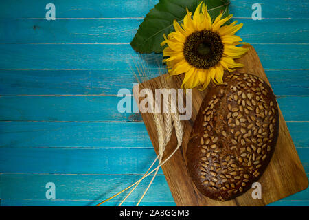Bread with sunflowers seeds, ear of ripe wheat and sunflower blossom on ...