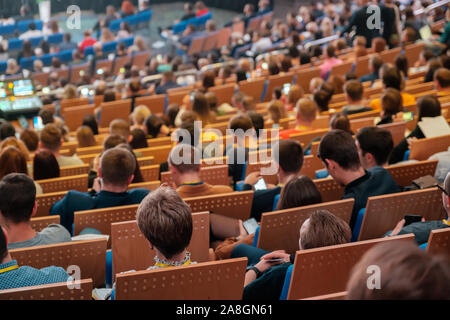 Business conference attendees sit and listen to lecturer, rear view ...