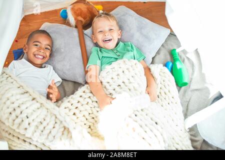 Adorable toddlers playing inside tipi around lots of toys at ...