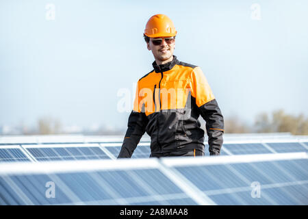 Well-equipped worker in protective orange clothing installing solar ...