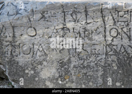 Half-erased ancient Greek letters embossed on an old gray marble slab ...