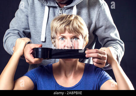 Man in hooded sweater covering a woman'smouth and holds a knife ...