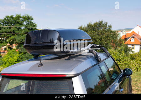 Modern car with black roof box covered in active white soap foam during ...