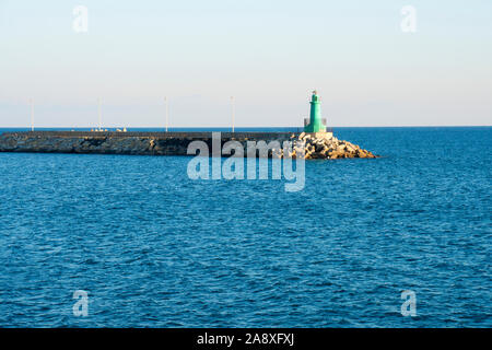Small green lighthouse at the entrance of a port Stock Photo - Alamy