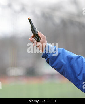Race official firing a pistol at the start of a race Stock Photo - Alamy