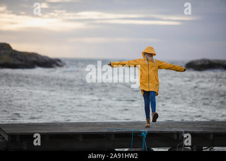 Young blonde woman standing over blue background backwards thinking ...