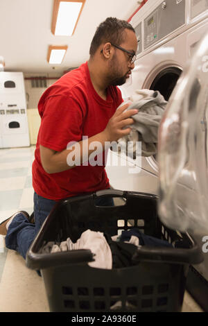 Young african man doing laundry holding eco friendly paper smiling ...