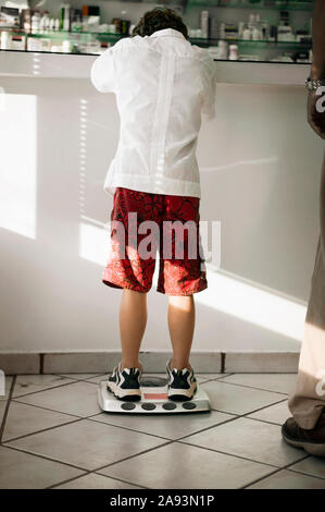 Rear view of a small boy checking his weight through the scale Stock ...