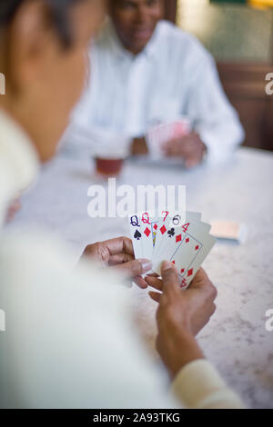 An adult male holds playing cards in front of his face. Hand with three ...