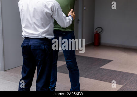Man being body searched for hidden objects by a guard at security ...
