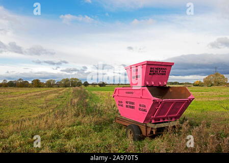Pink rubbish skips on display in the corner of a field, to advertise a ...