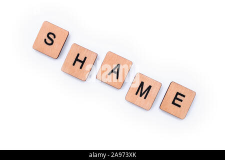 The word SHAME, spelt with wooden letter tiles over a white background ...