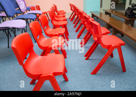 Preschool classroom with red chairs and table with drawings of children ...