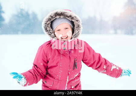 A cute Caucasian kid playing with the snow in the park in winter Stock ...