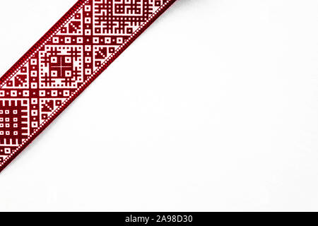 Red and white ribbon with ornament of Latvian signs on white background ...