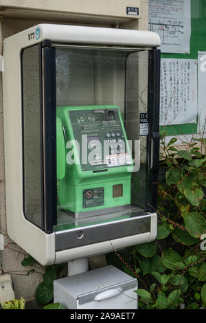 Old fashioned green Japanese NTT public telephone in a street in Kyoto ...