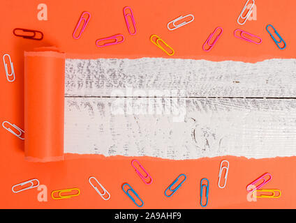 Paper clip and torn cardboard placed above a wooden classic table ...