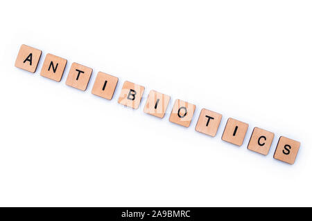 The word ANTIBIOTICS, spelt with wooden letter tiles over a white ...