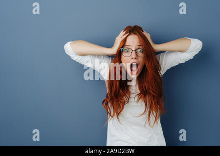 Horrified young woman staring wide-eyed at her tablet Stock Photo - Alamy