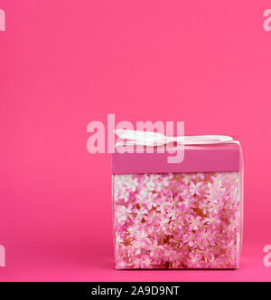 closed pink cardboard box with a bow on a blue background, top view ...