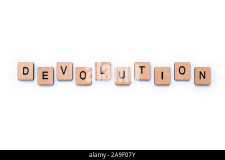 The word DEVOLUTION, spelt with wooden letter tiles over a plain white ...