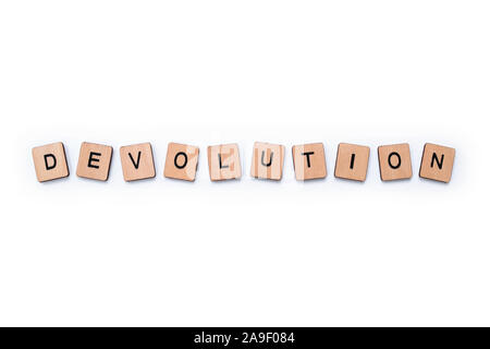 The word DEVOLUTION, spelt with wooden letter tiles over a plain white ...
